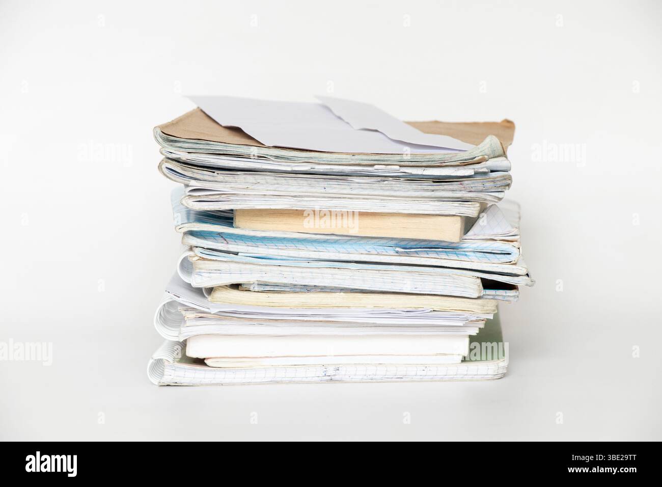 A stack of old notebooks, notepads and books on a white background, a ...