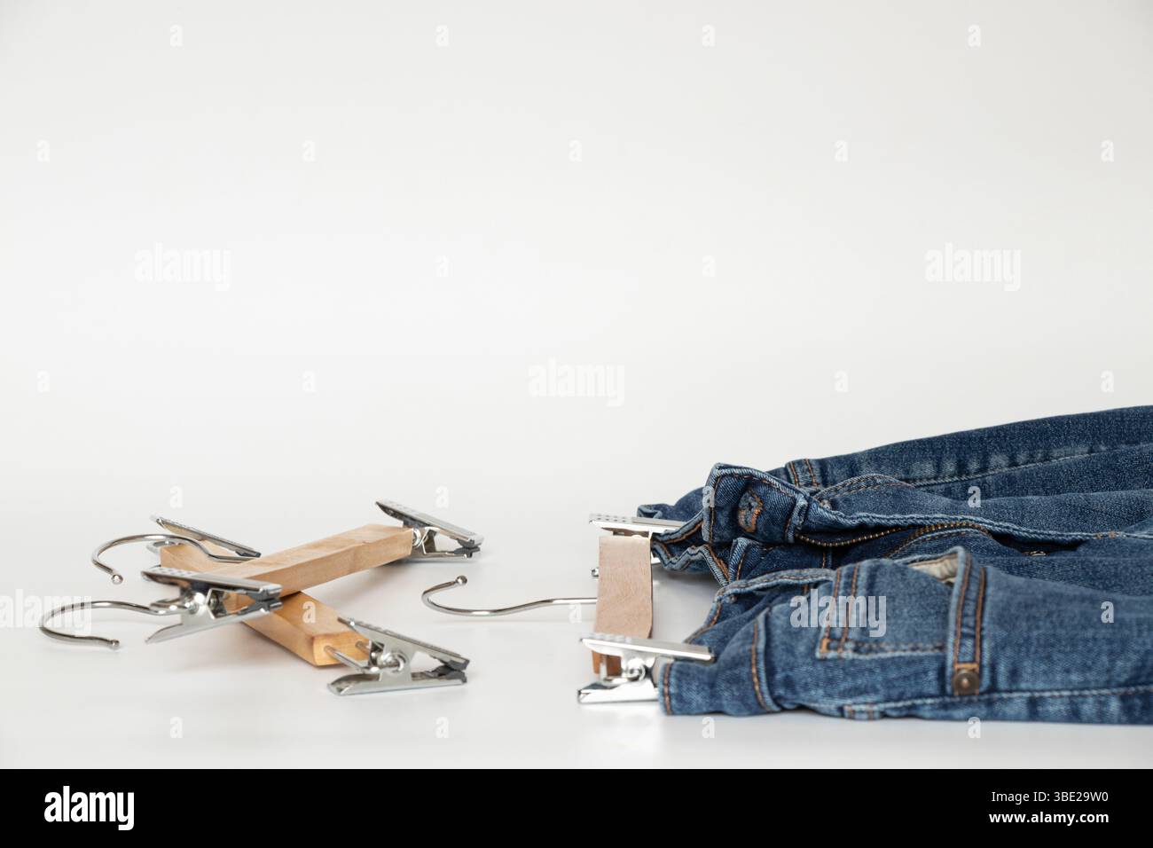 Folded blue jeans with wooden hangers on white background, basic men's ...