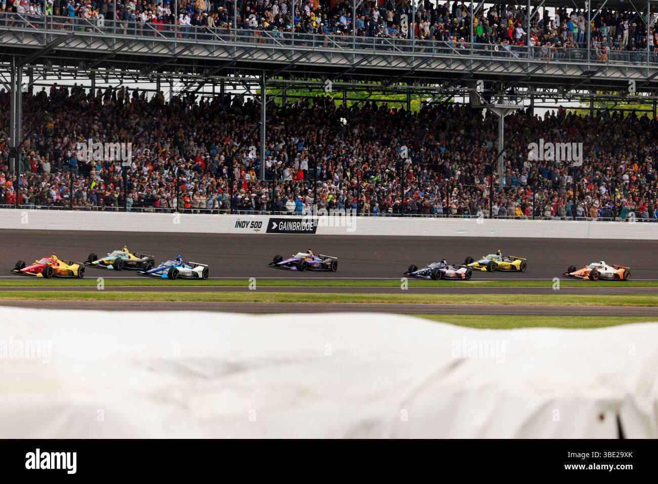 Indianapolis, United States. 25th May, 2025. Cars speed through turn ...