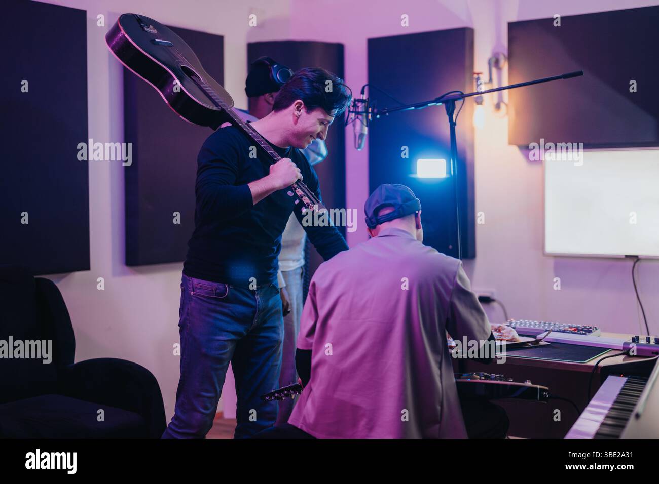 Musicians collaborating in modern recording studio with acoustic guitar ...