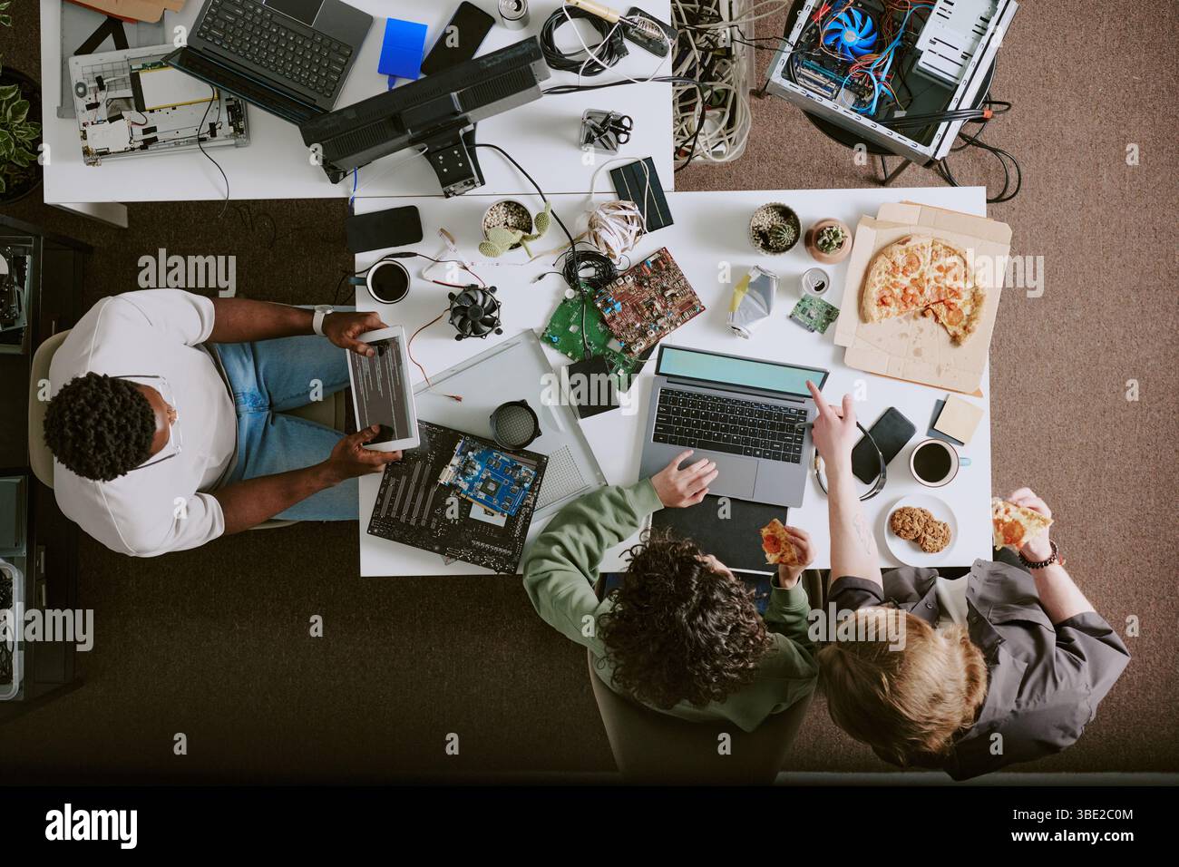 Group of people discussing at cluttered workspace with various ...