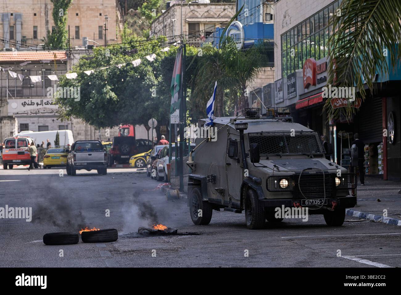 An Israeli armoured vehicle drives near burning tires during a military ...