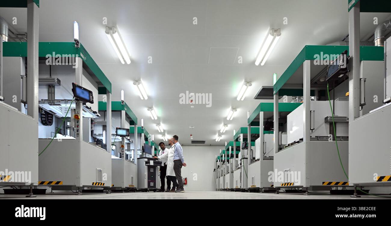 27 May 2025, Thuringia, Arnstadt: Employees stand at a workstation in ...