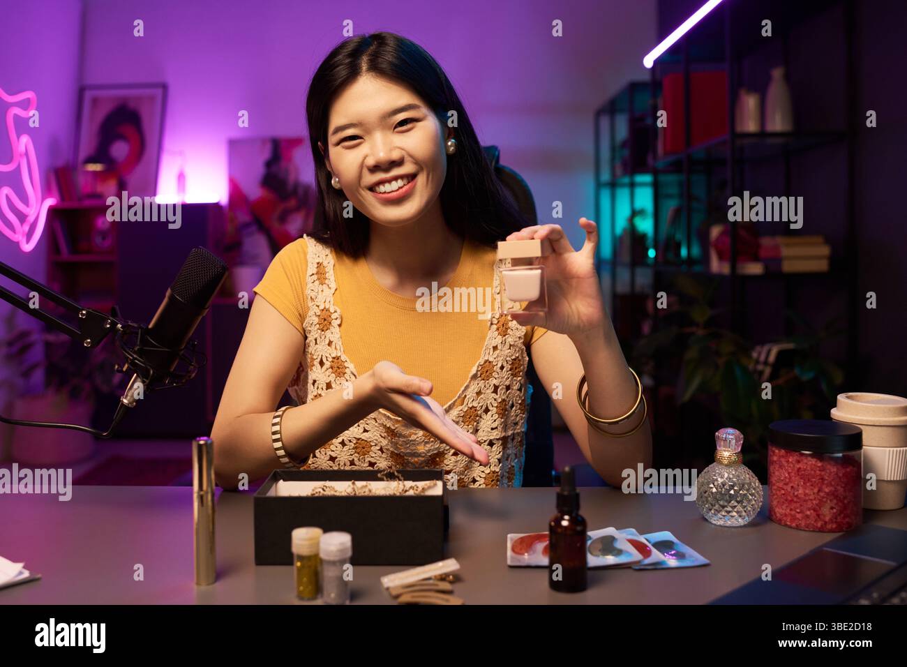 Woman demonstrating beauty products at desk with vibrant background ...