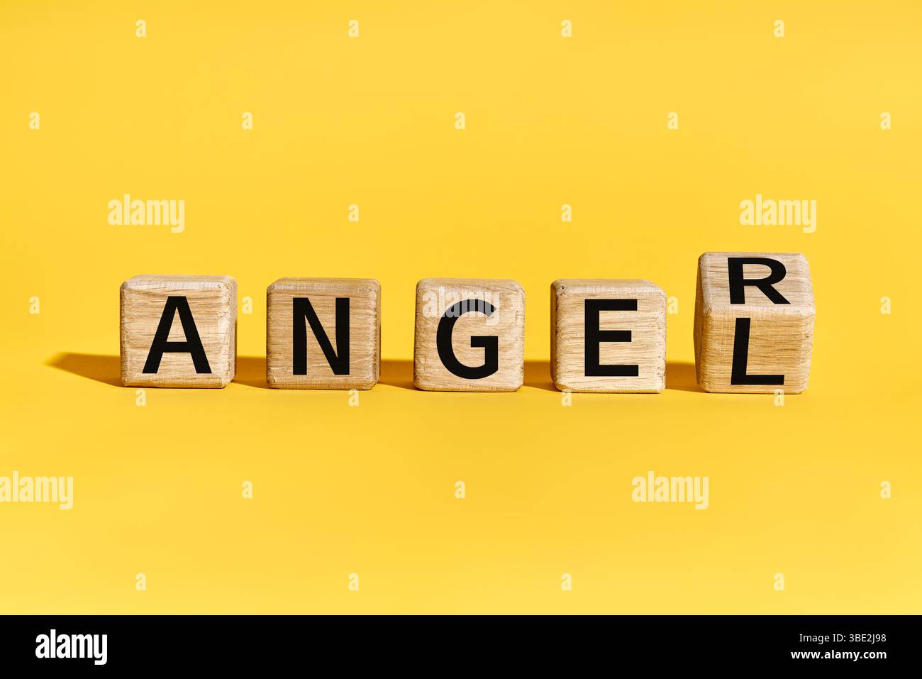 Wooden blocks forming words ANGEL to ANGER over yellow background ...