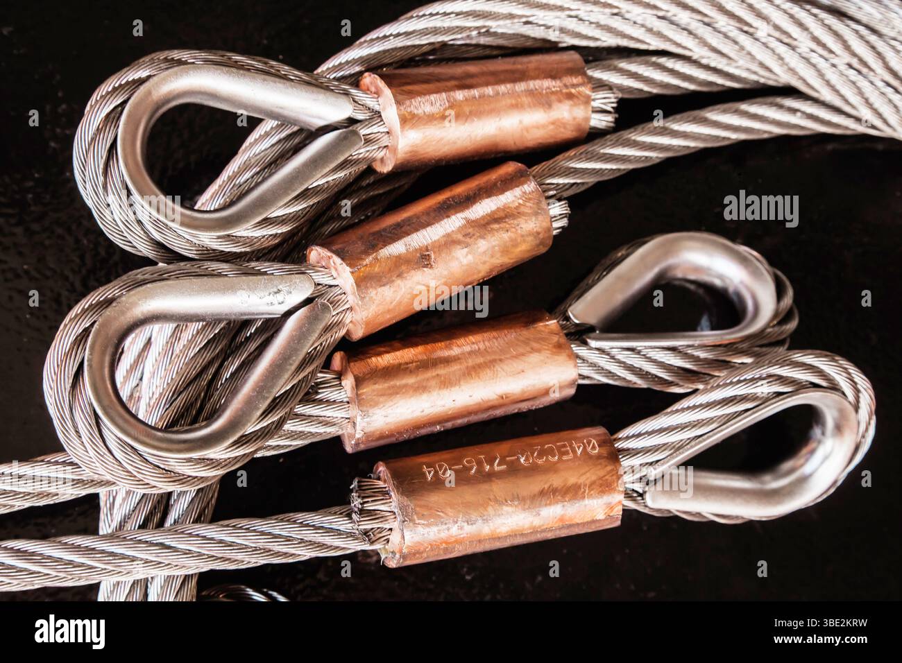 Stainless steel cable, with loops and copper clamps, and a black ...