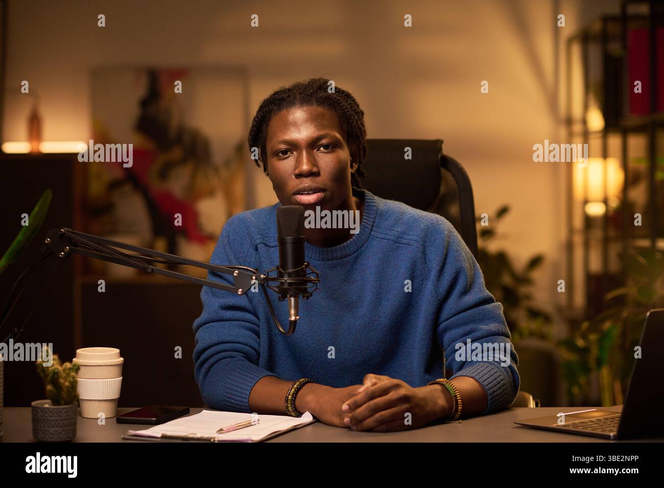 Portrait of an African American man sitting at desk, speaking into ...