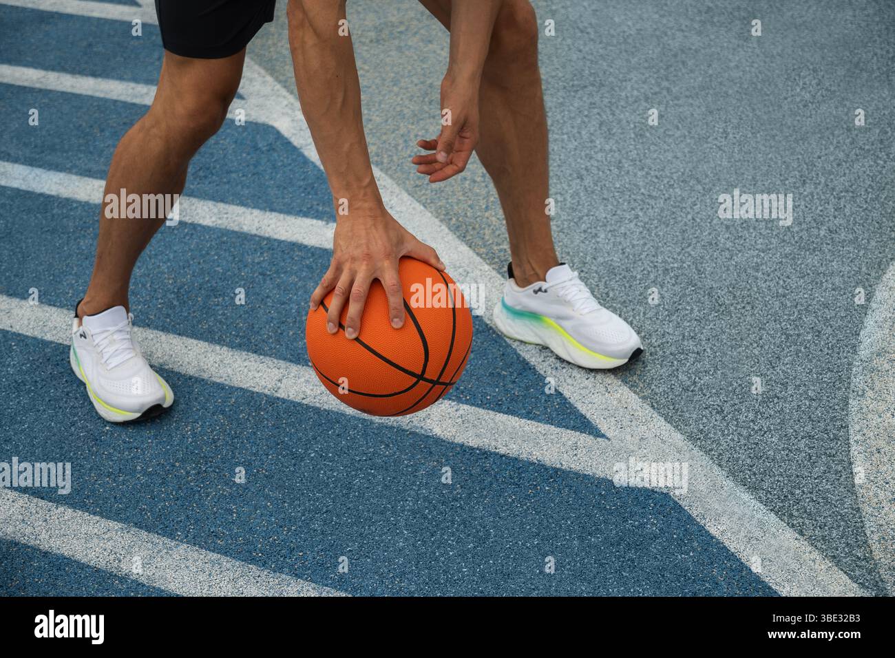 Basketball player dribbling ball, capturing motion and shadow on blue ...