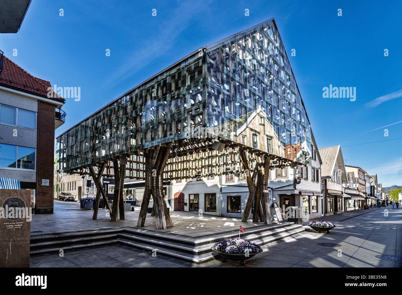 A striking modern glass building surrounded by traditional structures ...