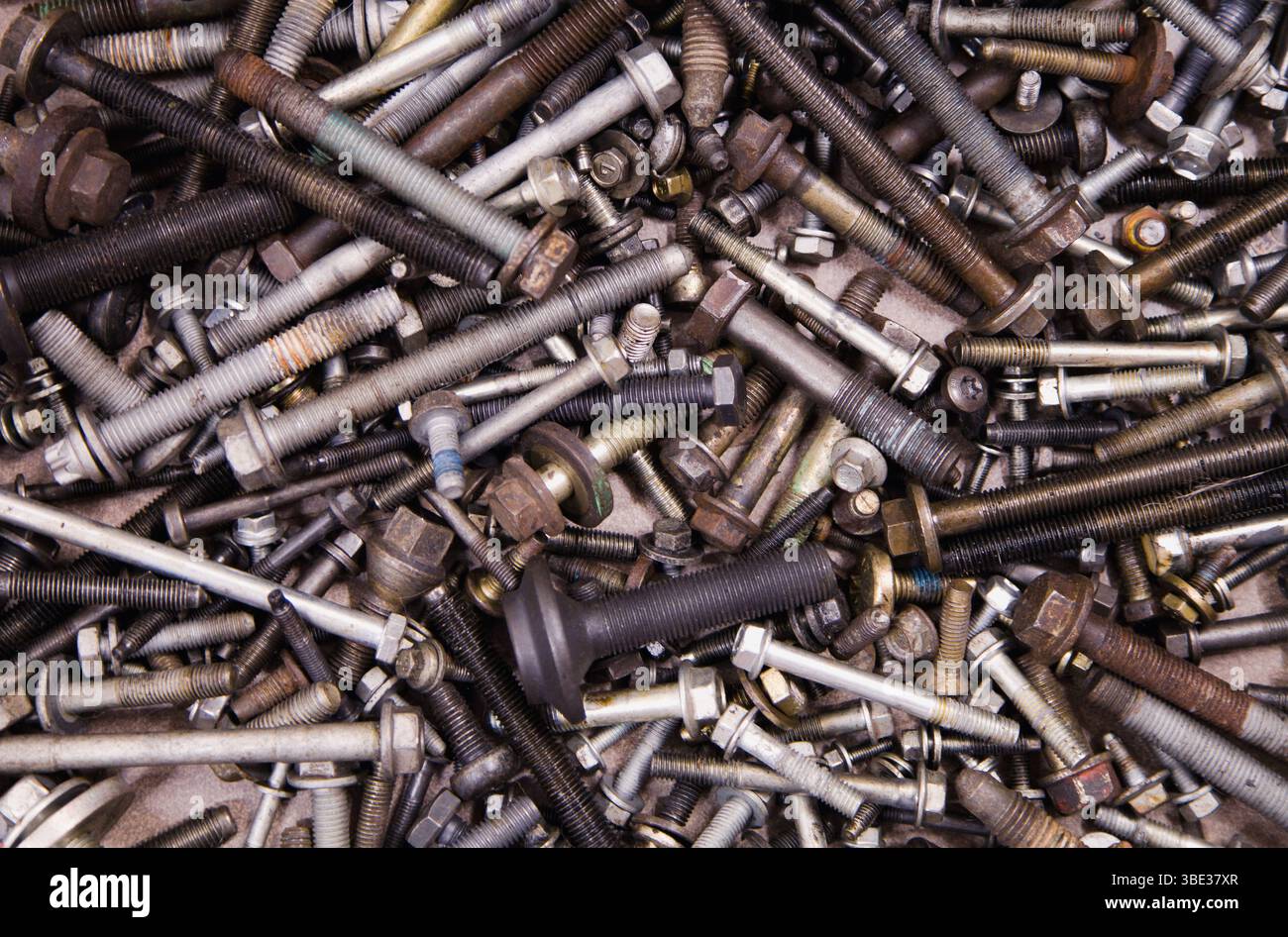 Scattered bolts and screws of different sizes forming an industrial ...