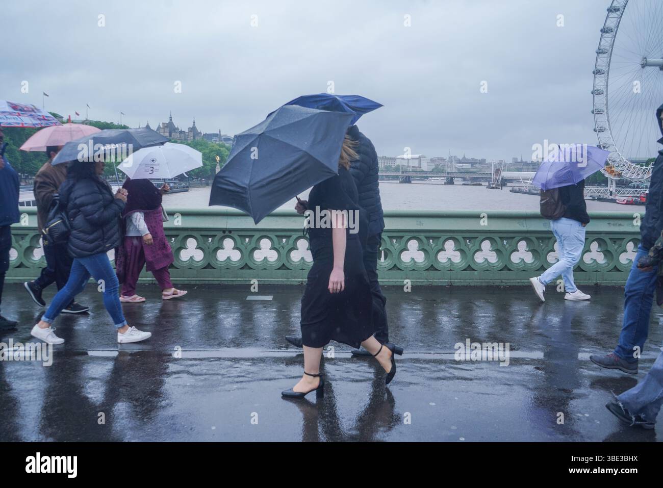 London, UK. 27 May 2025. Pedestrians on Westminster Bridge brave the ...