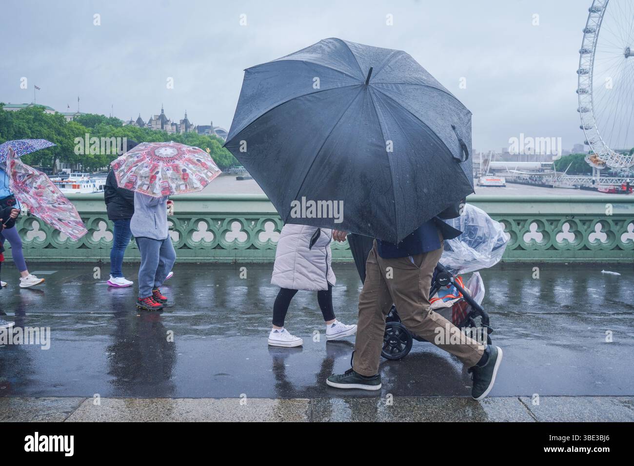 London, UK. 27 May 2025. Pedestrians on Westminster Bridge brave the ...