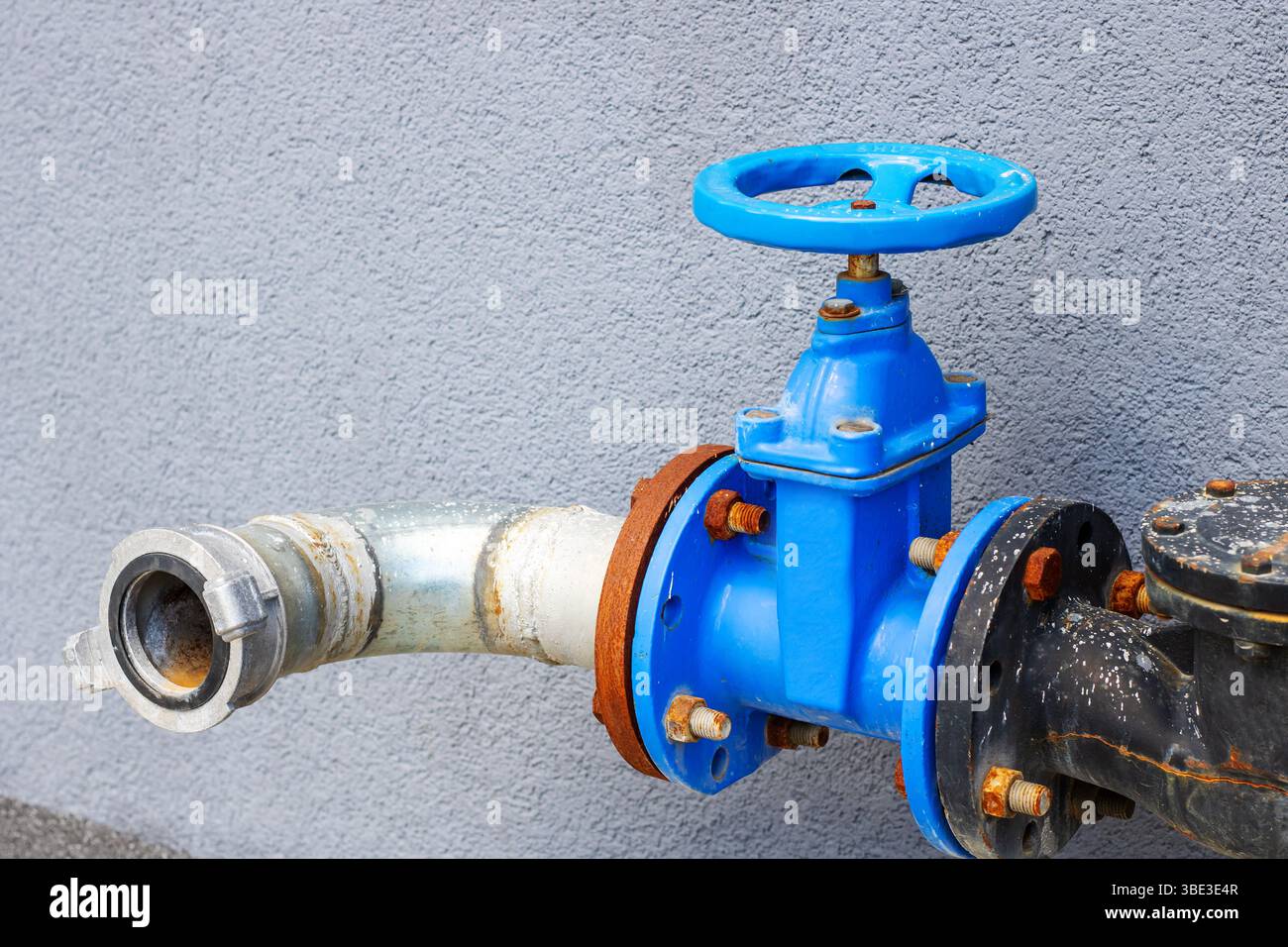 A bright blue valve is securely fastened to a sturdy metal pipe, which ...