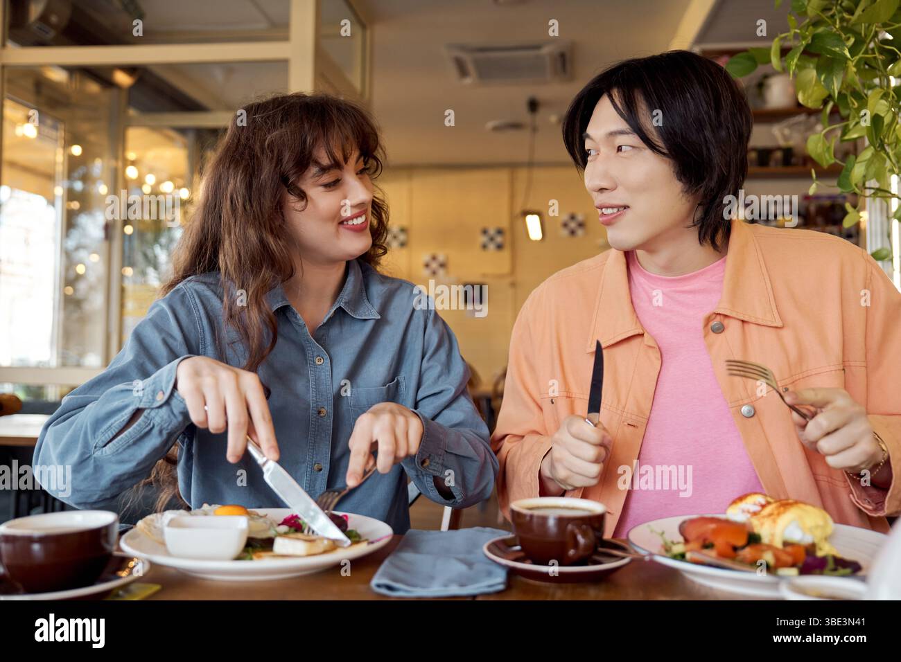 Two young friends sharing a joyful meal together in a vibrant cafe ...