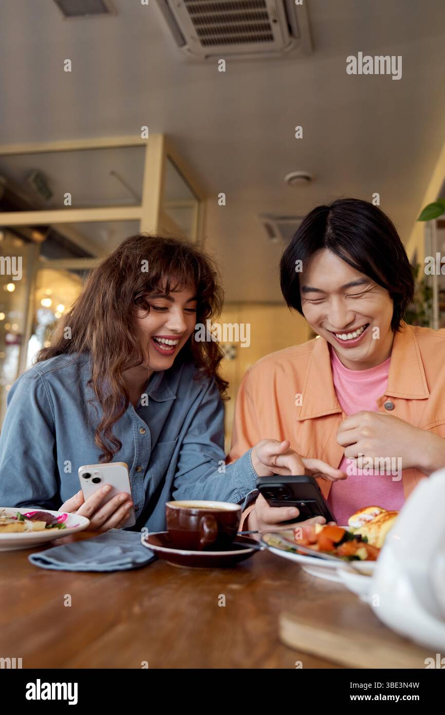 Two multicultural friends enjoy laughter and meals together in a ...