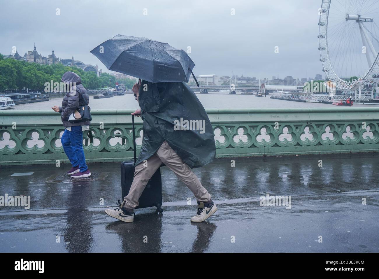 London, UK. 27 May 2025. Pedestrians on Westminster Bridge brave the ...