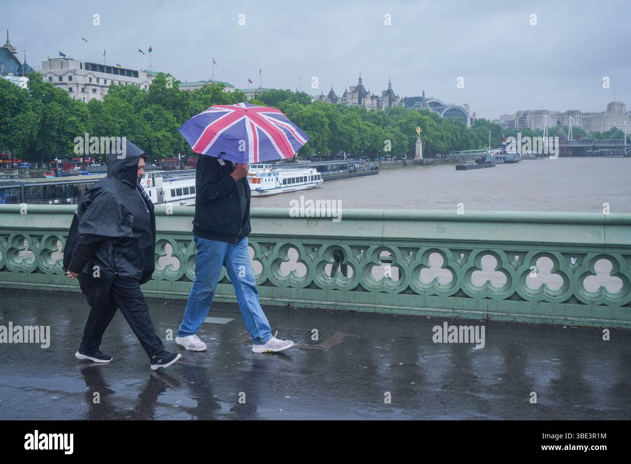 London, UK. 27 May 2025. Pedestrians on Westminster Bridge brave the ...