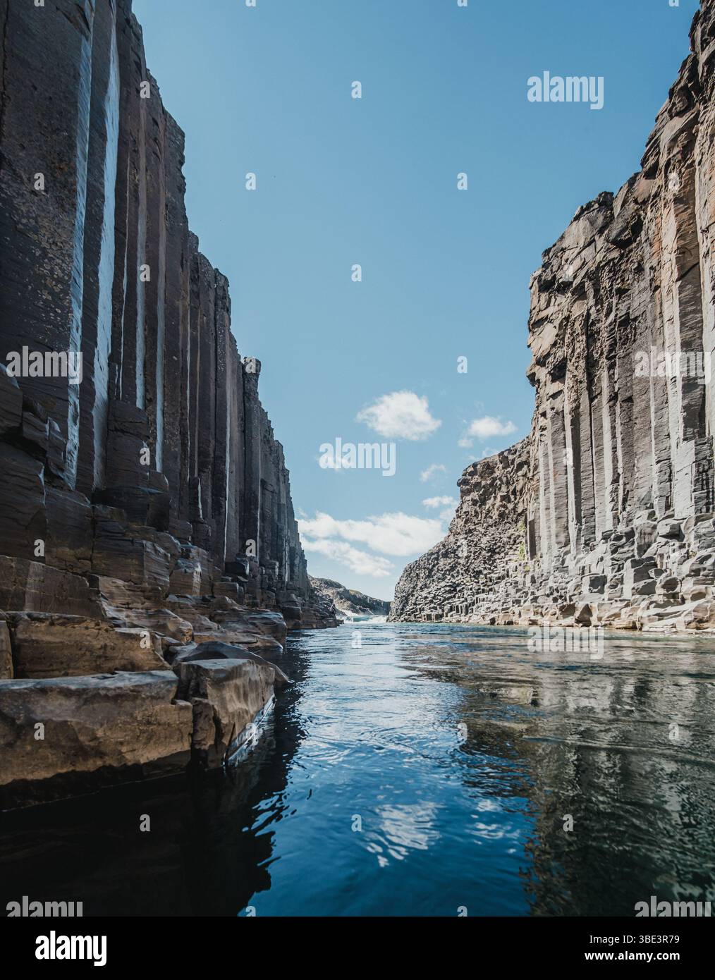 Basalt cliffs rising over glacial river in Studlagil canyon, East ...