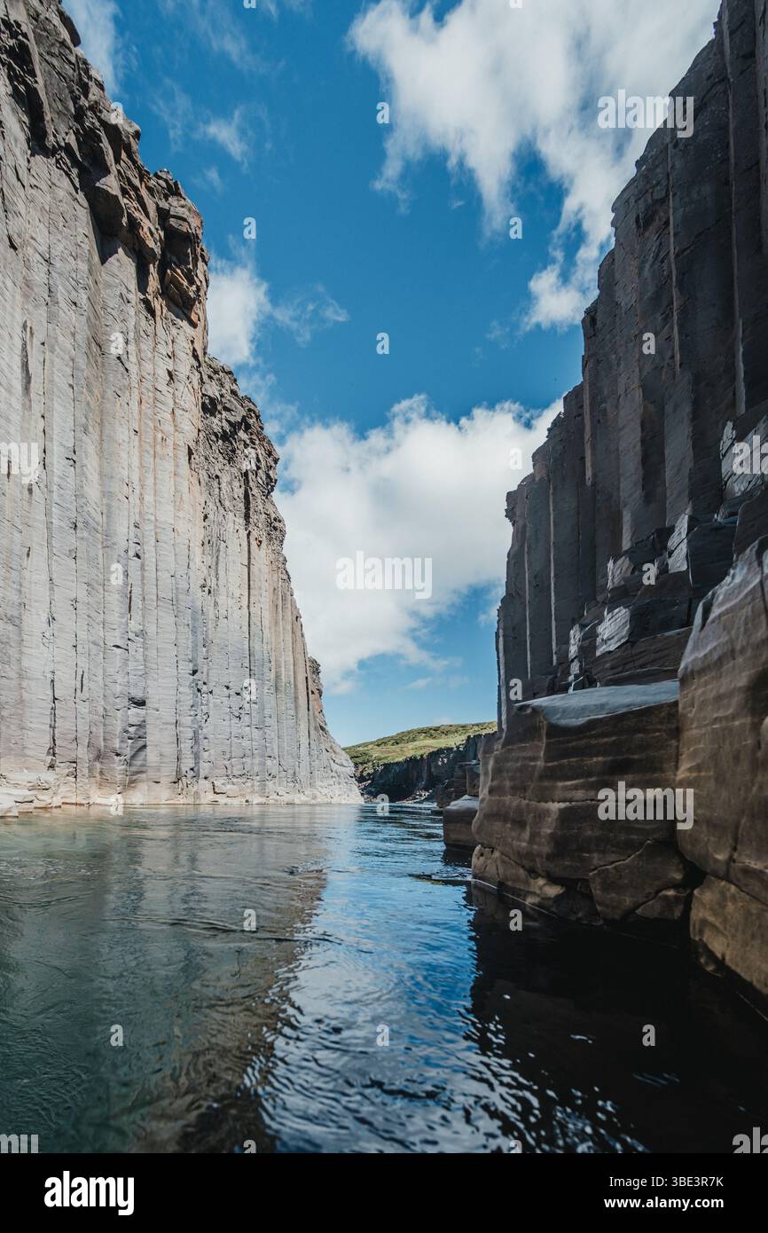 Basalt cliffs rising over glacial river in Studlagil canyon, East ...