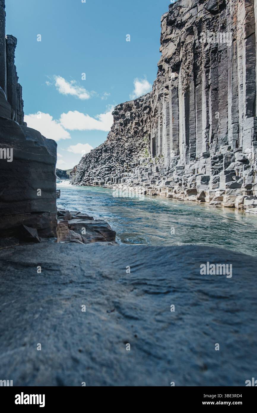 Basalt cliffs rising over glacial river in Studlagil canyon, East ...