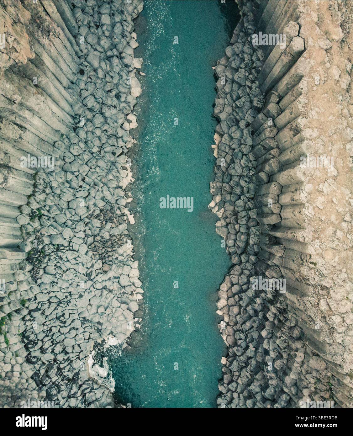 Aerial view of turquoise river slicing through basalt columns ...