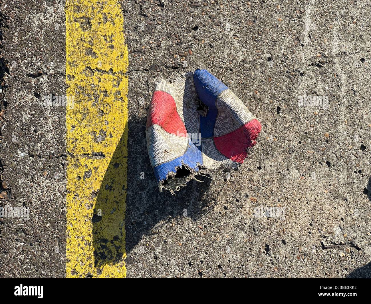 A deflated, weathered basketball with faded red, white, and blue panels ...