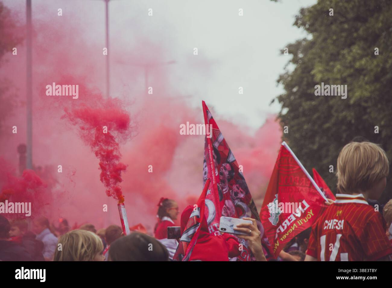 Crowds of Liverpool fans with red smoke bombs and flags on Queens Drive ...