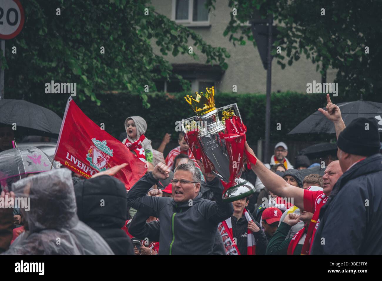 Male Liverpool supporters waving a replica Premier League trophy in a ...