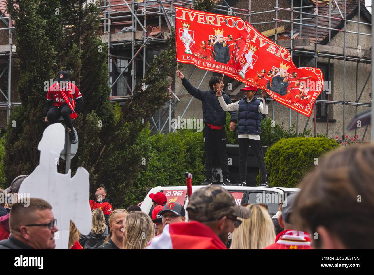 Young Liverpool supporters stood on a van waving red flags, with a ...