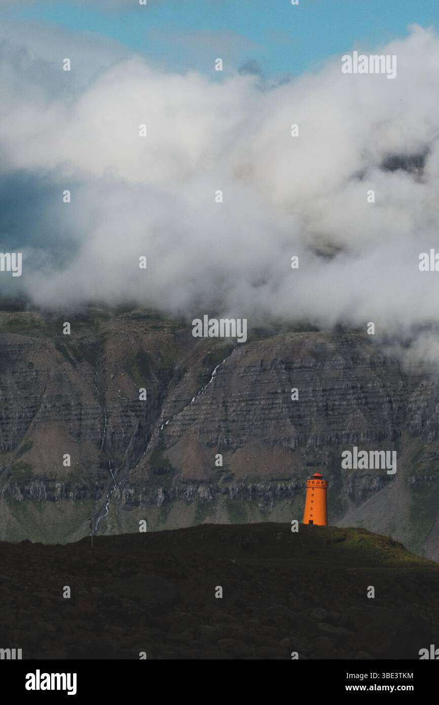 Vattarnes lighthouse standing beneath misty cliffs in Reydafjordur ...