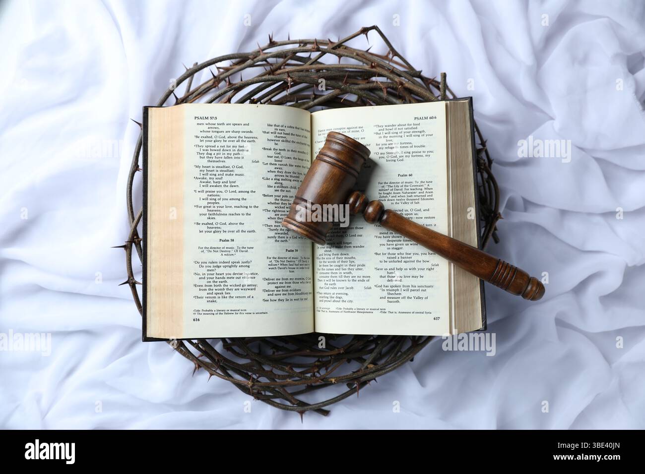 Judge's gavel, crown of thorns and Bible on white fabric, top view ...