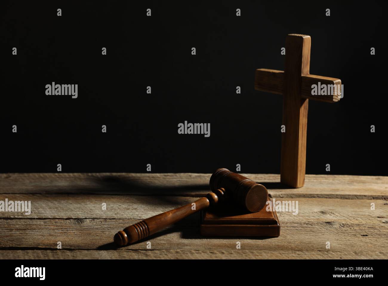 Judge's gavel and cross on wooden table against black background Stock ...