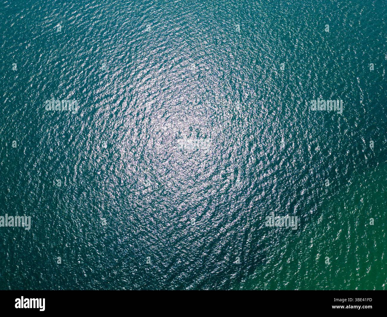 Aerial view of sun reflections on the surface of rippling turquoise sea ...