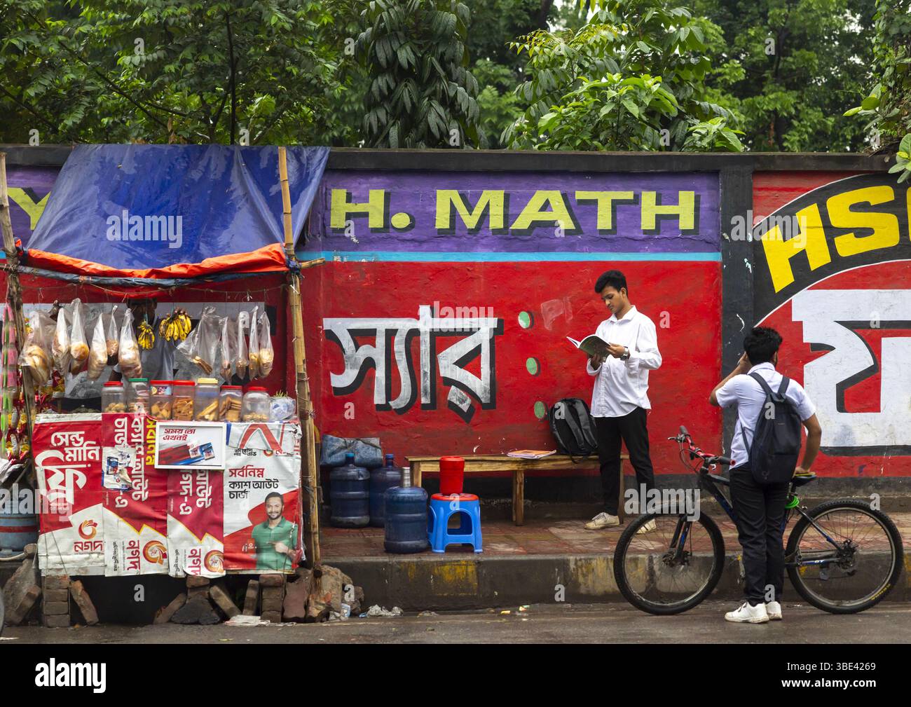 Bangladeshi man reading a book near a street food stall, Dhaka Division, Dhaka, Bangladesh Stock ...