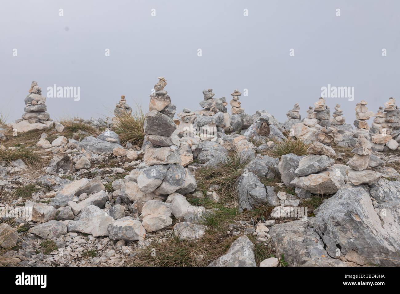 Stacked stone cairns dot barren mountain plateau under grey sky ...