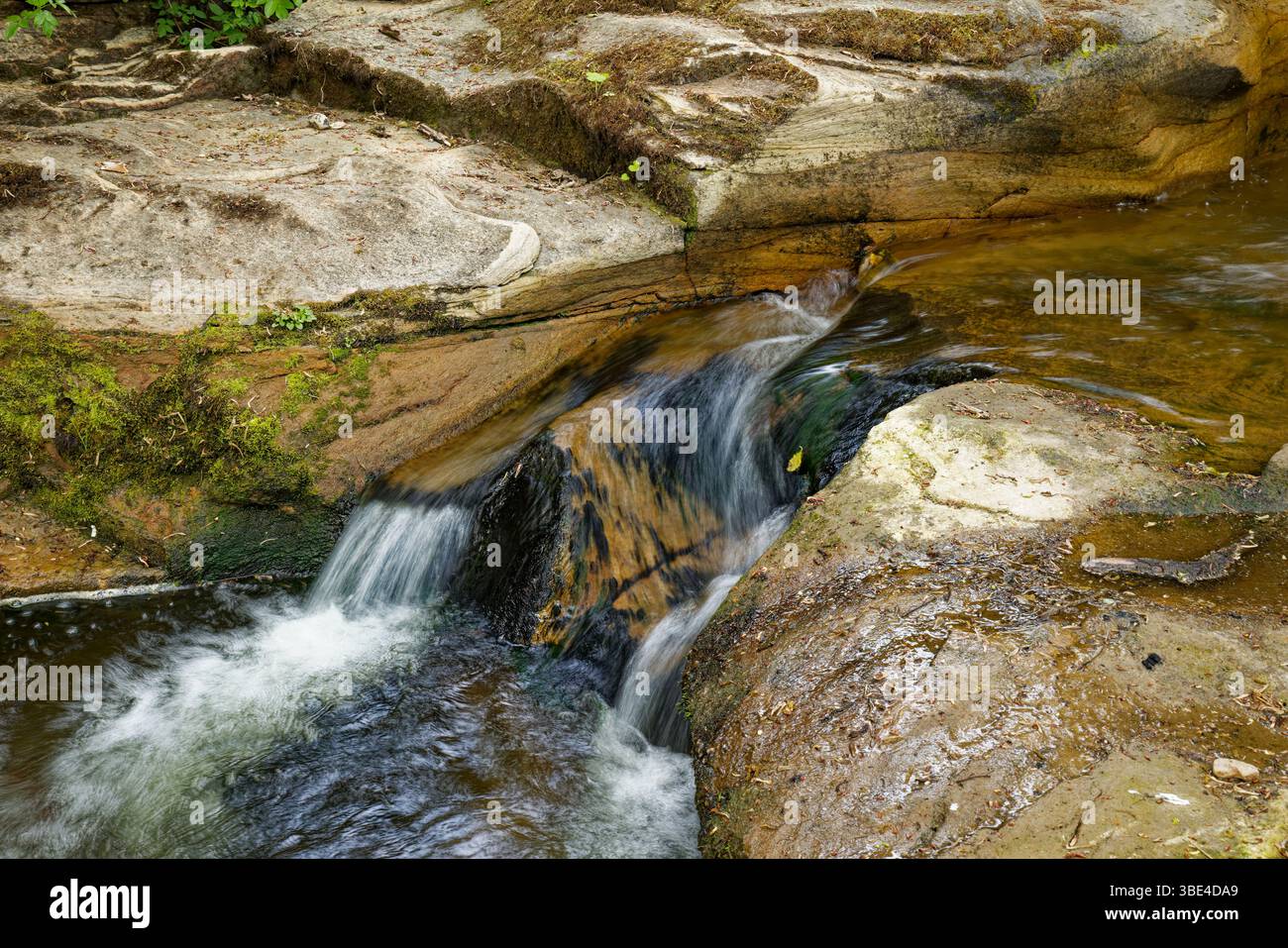 Water flows gently over smooth rocks of a river bed Stock Photo - Alamy