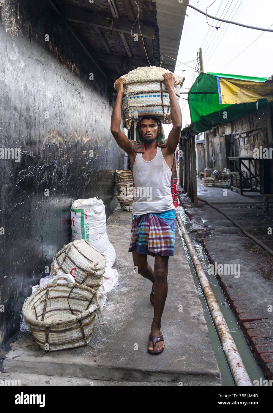 Bangladeshi man weighing basket with salt at a factory, Chittagong ...
