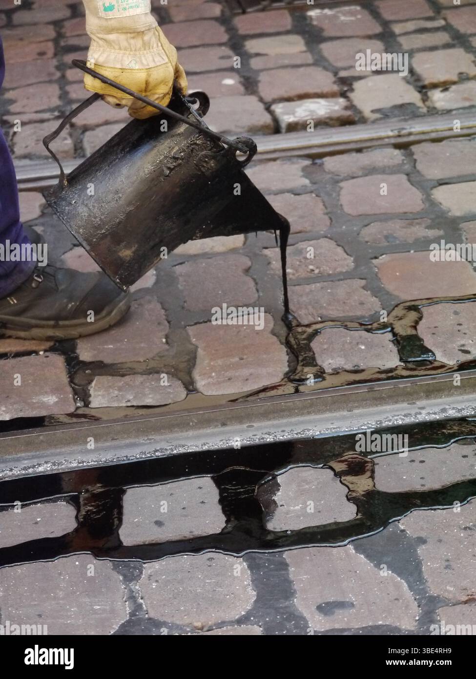 Man is pouring black liquid into a bucket Stock Photo - Alamy