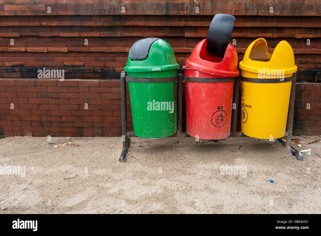 Three trash cans are lined up in a row, each with a different color ...