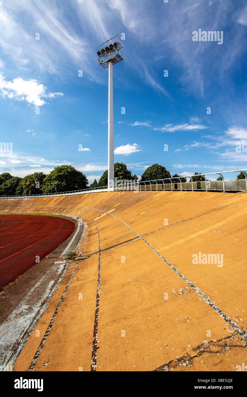 Bright daylight reveals an empty sports stadium with a cycle track. The ...