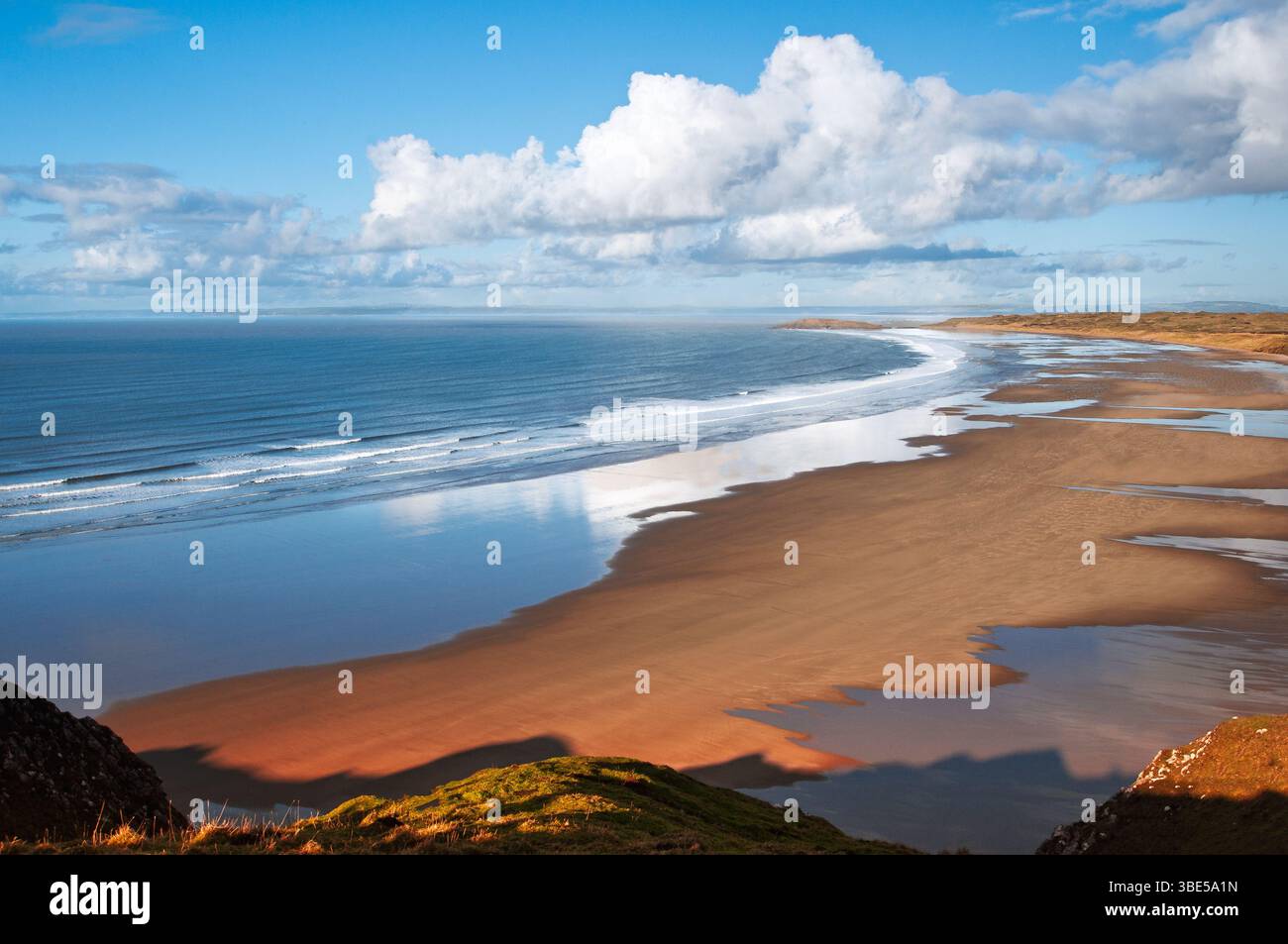 A scenic view of Rhossili Bay in Wales, showcasing the vast sandy beach ...
