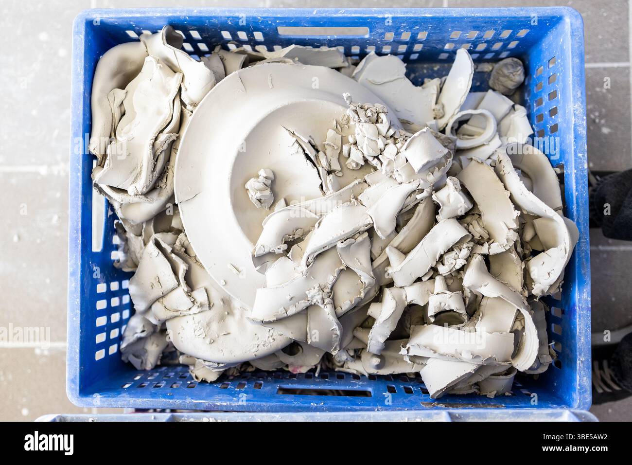 above view of shards and fragments of unfired porcelain in plastic box ...