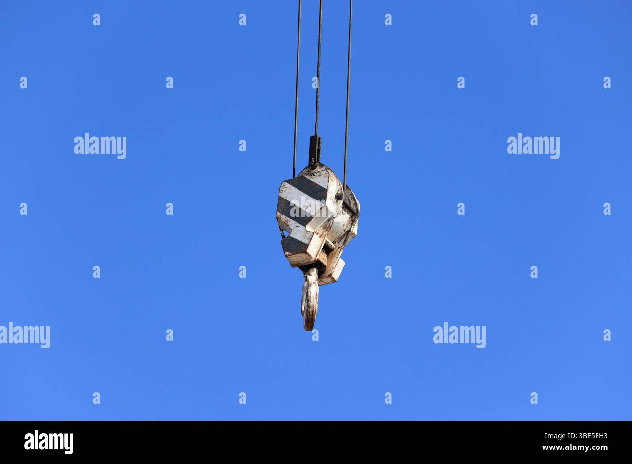 CRane pulley block and hooh attached to steel cables with blue sky and ...