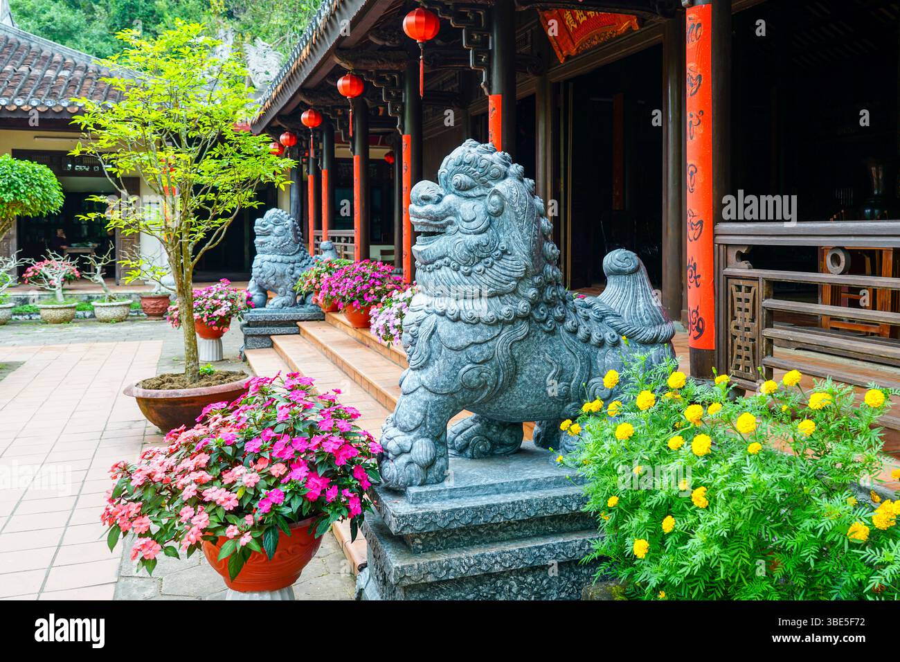 Stone guardian lion statues with blooming flowers and red lanterns in ...