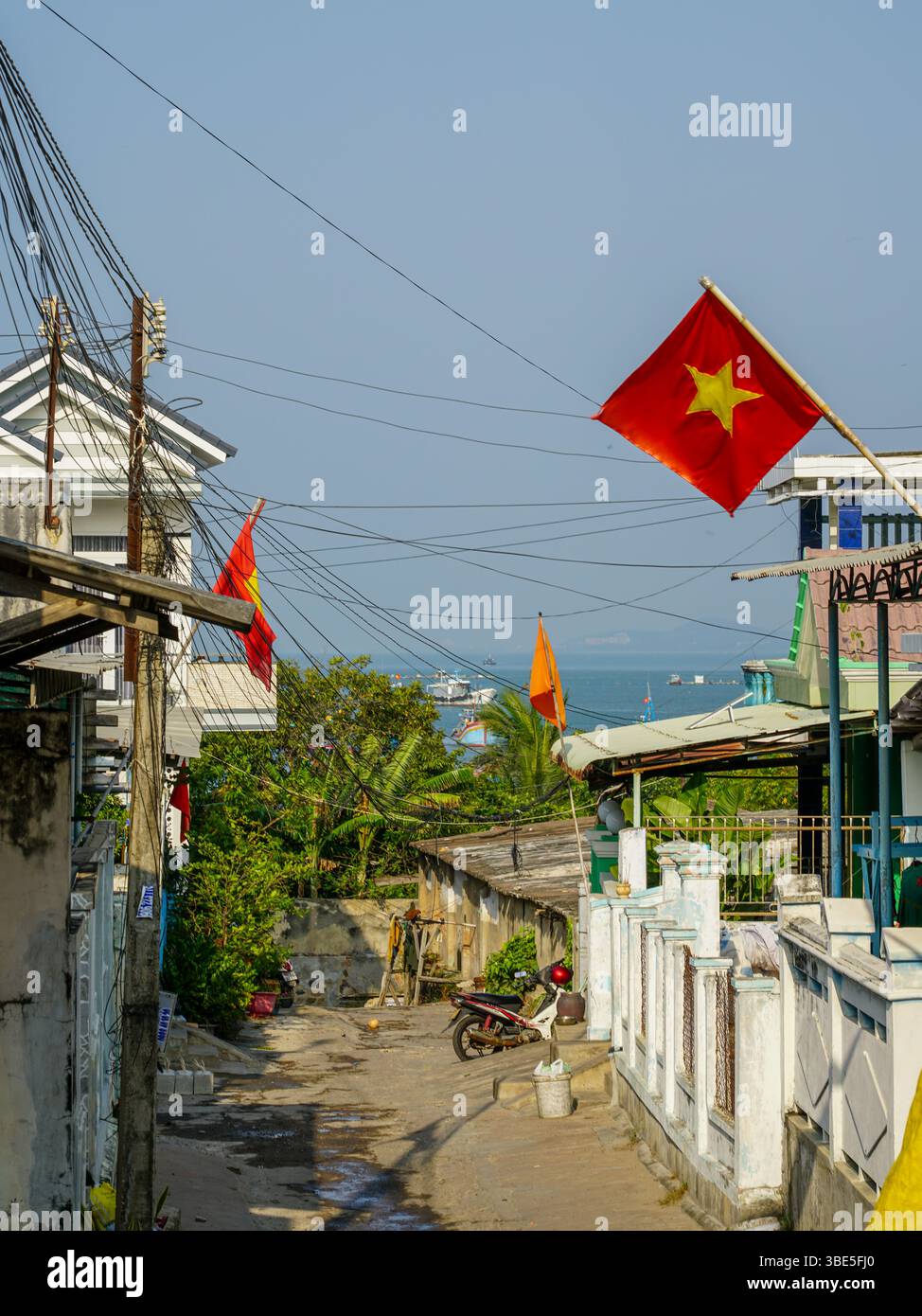 Narrow Vietnamese alleyway adorned with red flags, motorbikes, power ...