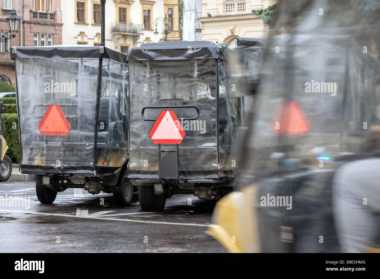 several garbage or cargo carts with orange triangular warning signs on ...