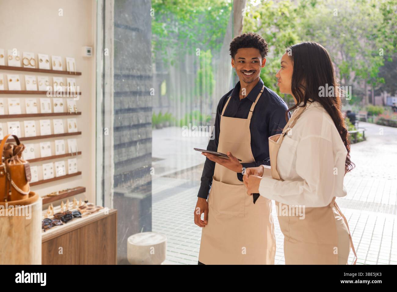 Two store employees in aprons engage in a conversation about product ...