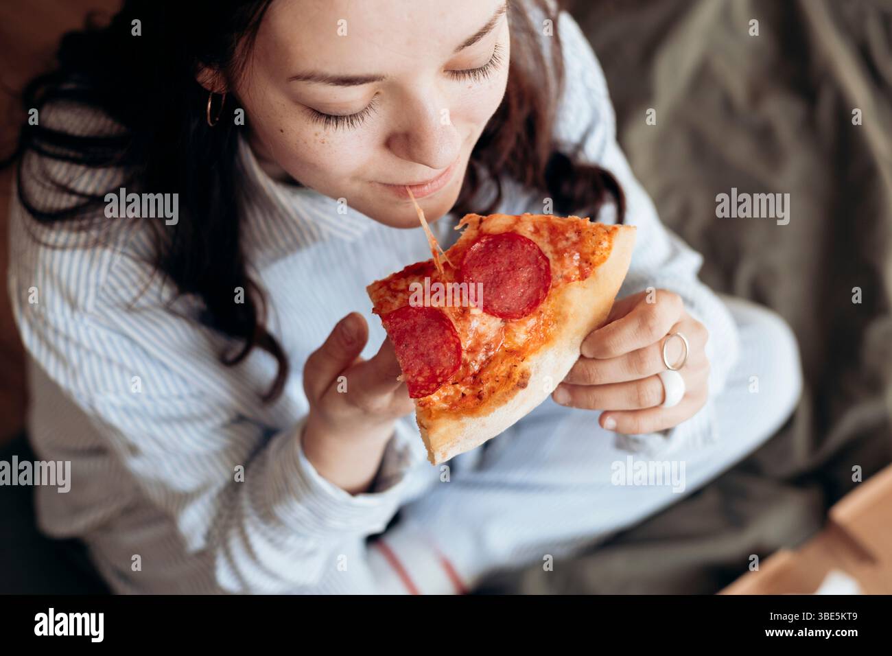 From above image of woman captured in the comfort of her bed savoring a ...