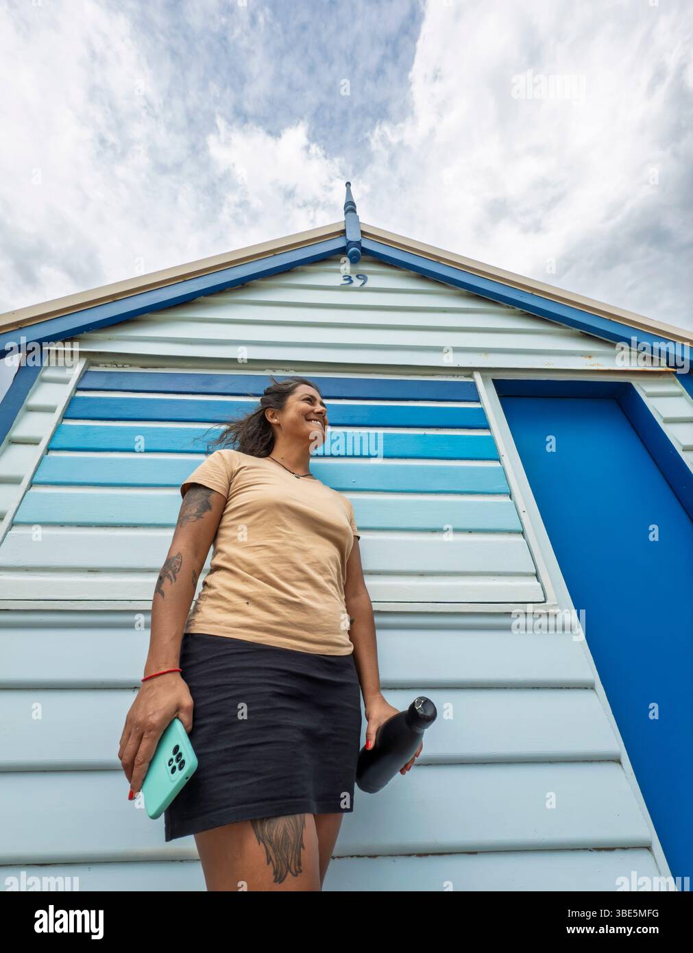 A woman stands in front of the iconic Brighton Bathing Boxes in ...