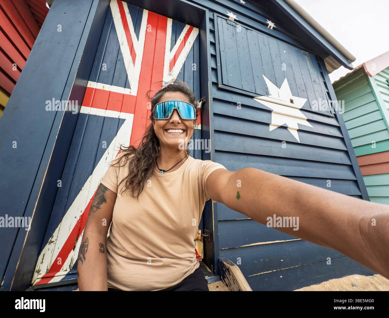 A cheerful woman takes a selfie in front of the iconic Brighton Bathing ...